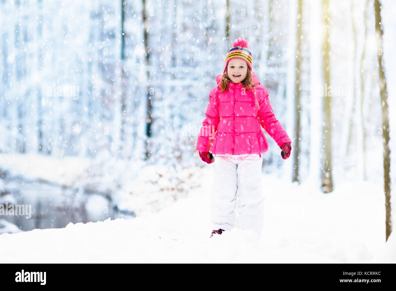 Child playing with snow in winter. Little girl in colorful jacket and ...