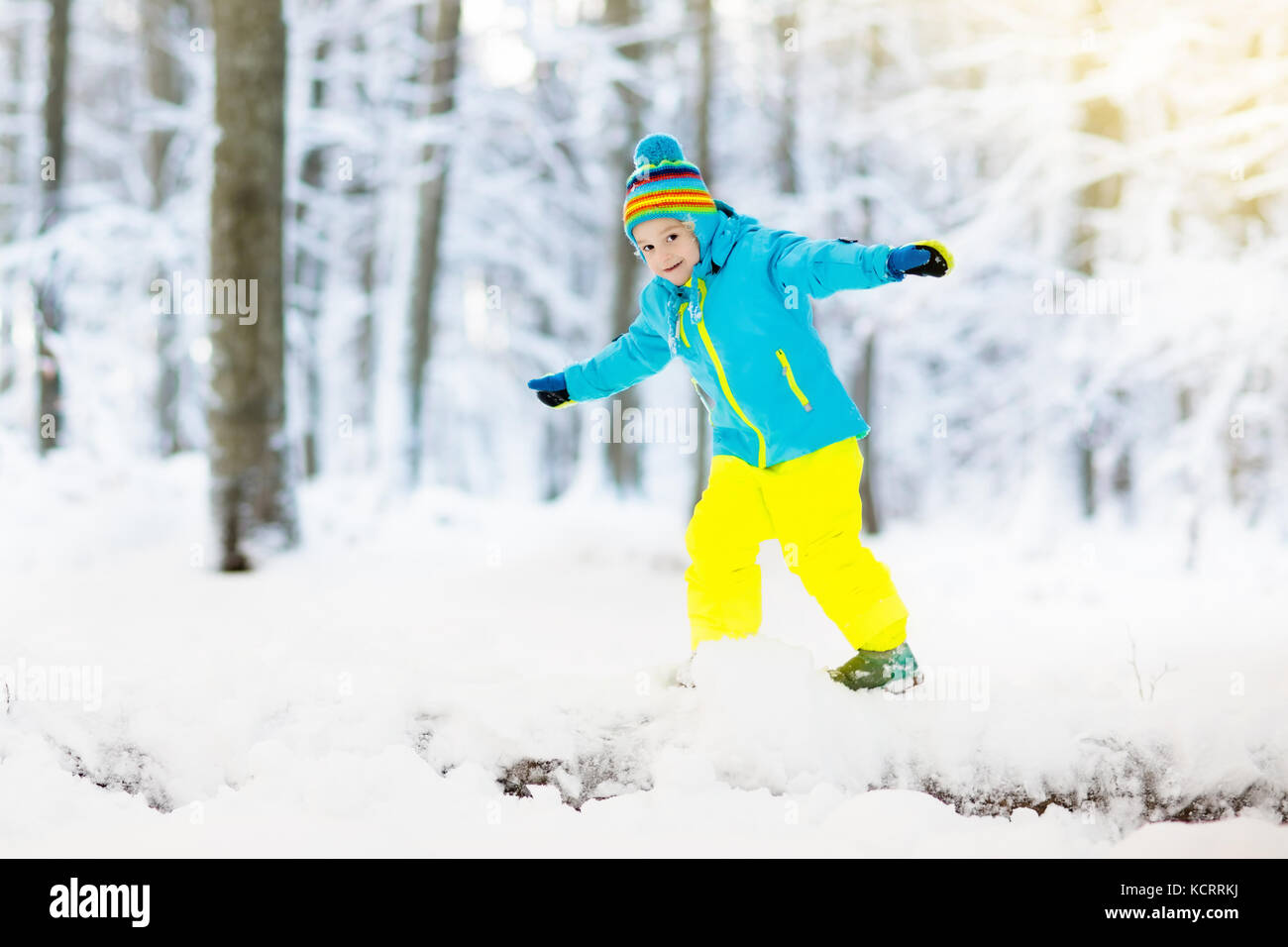 Child playing with snow in winter. Little boy in colorful jacket and ...