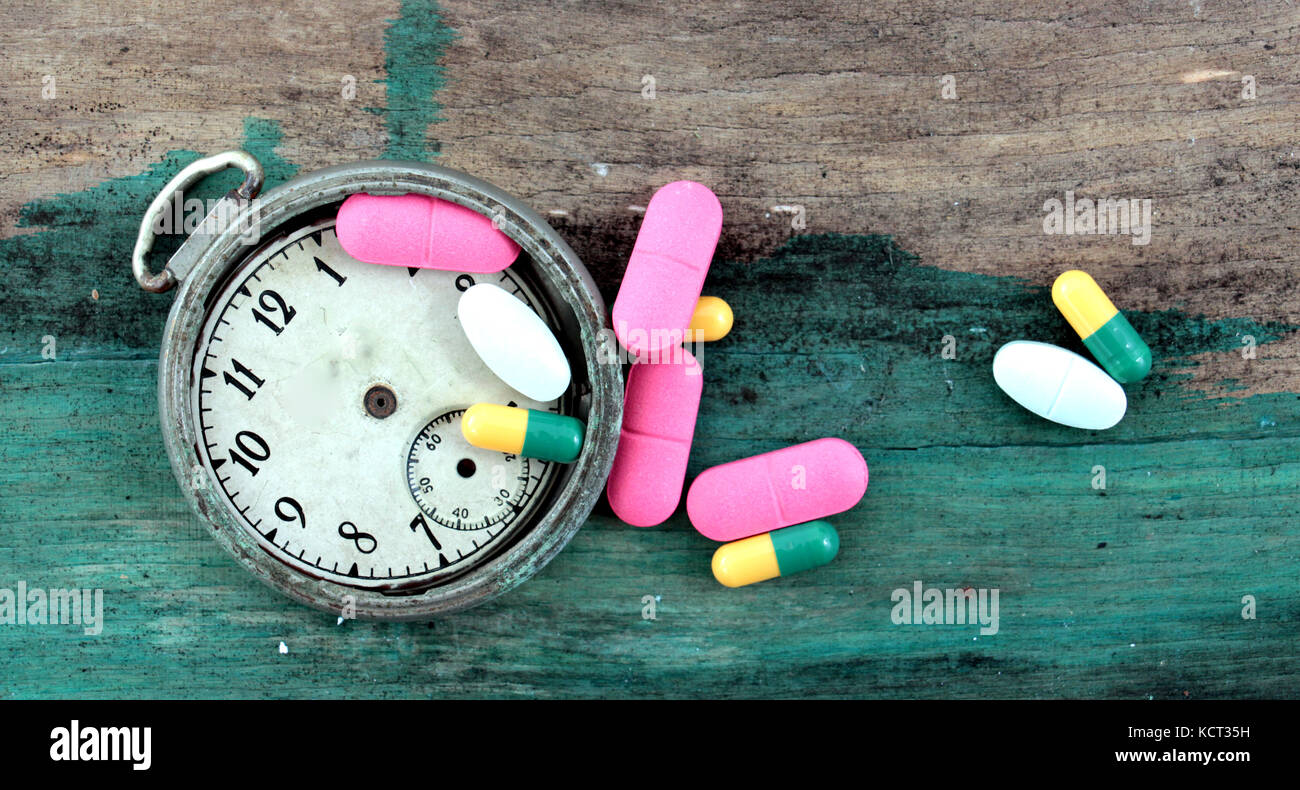 Many colorful pills and capsules and vintage clock Stock Photo - Alamy