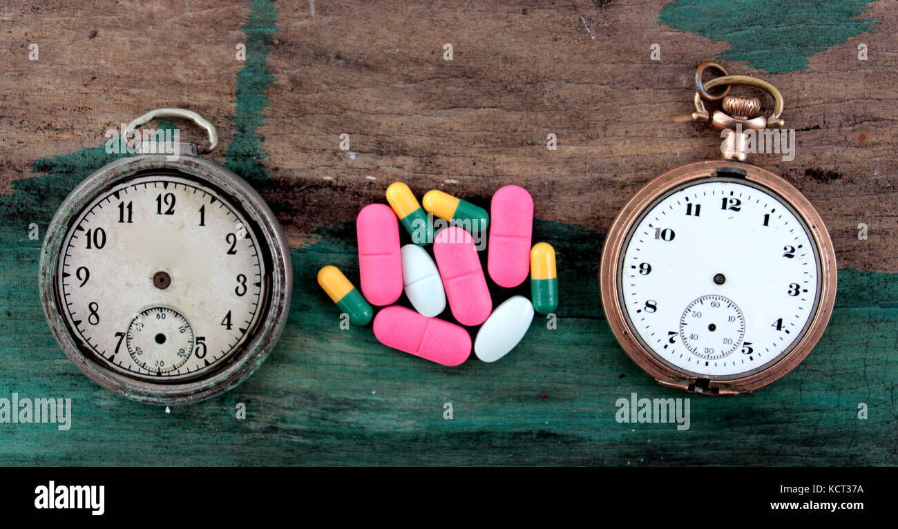 Many colorful pills and capsules and vintage clock Stock Photo - Alamy