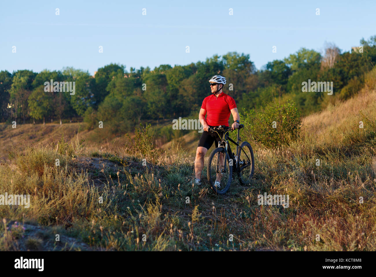 young bright man on mountain bike riding in autumn landscape against ...