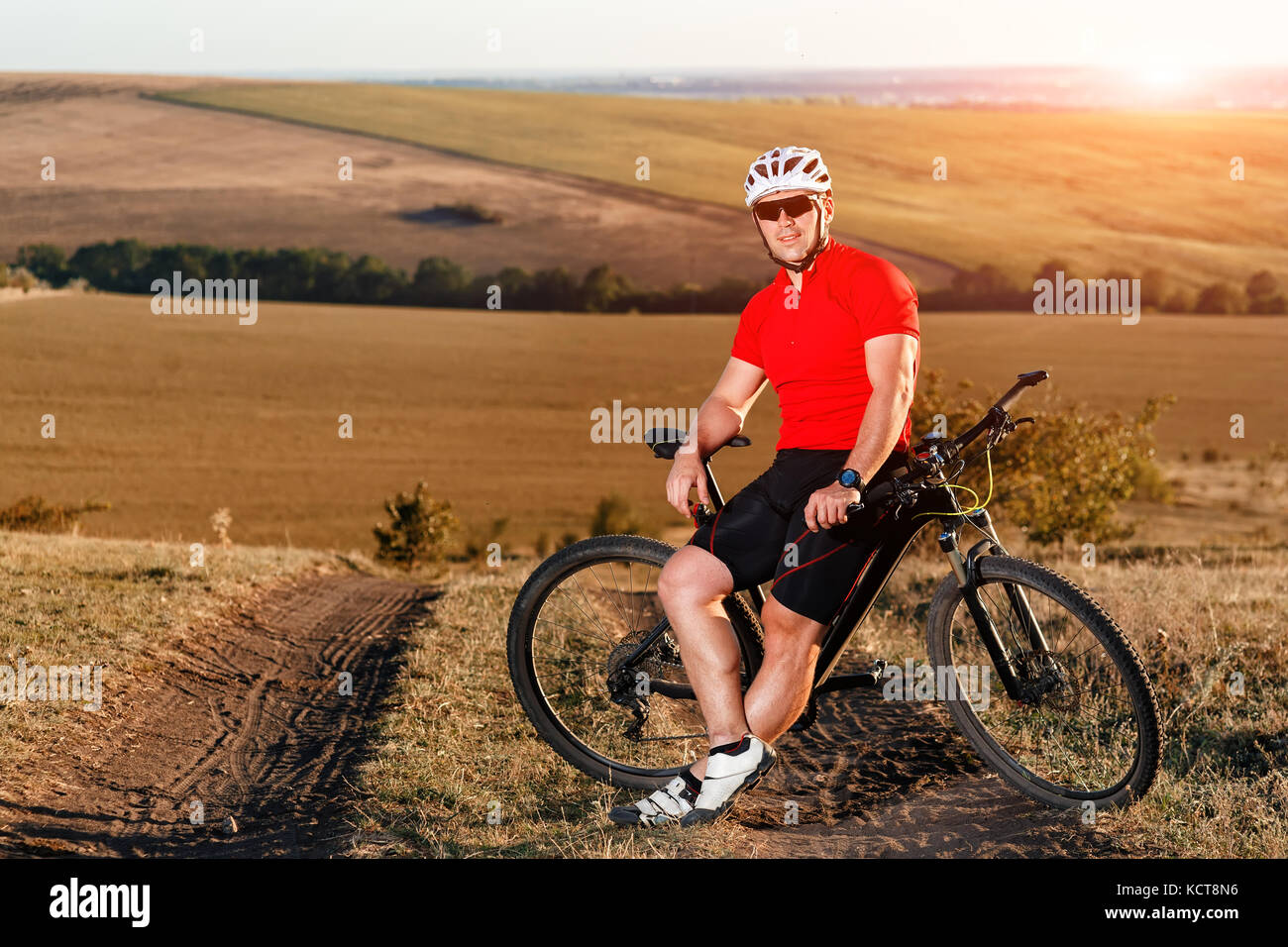 young bright man on mountain bike riding in autumn landscape against ...