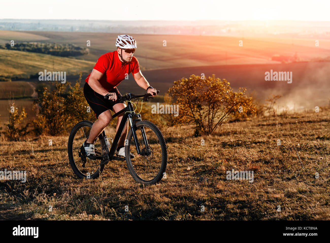 young bright man on mountain bike riding in autumn landscape against ...
