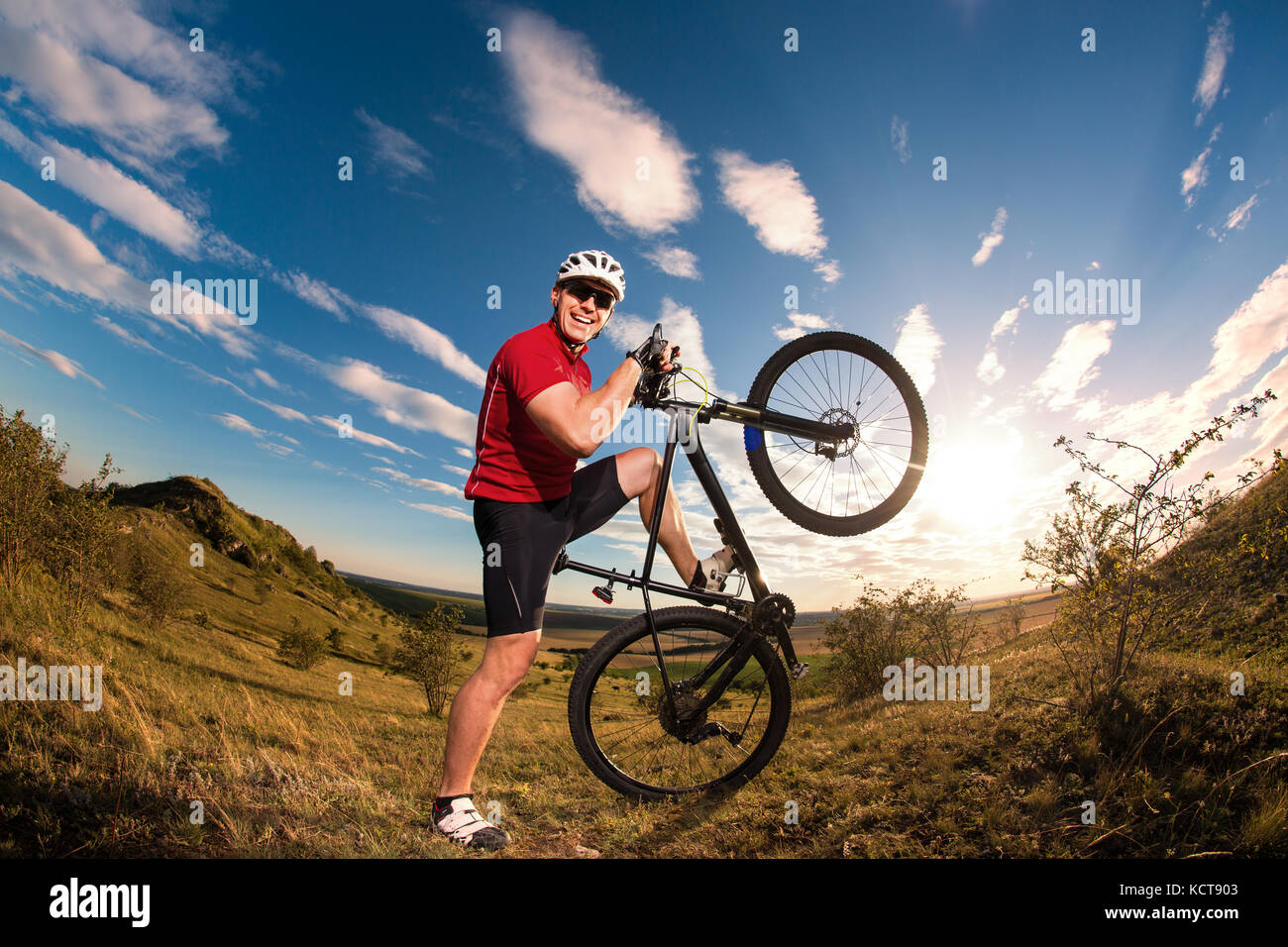 young bright man on mountain bike riding in autumn landscape against ...