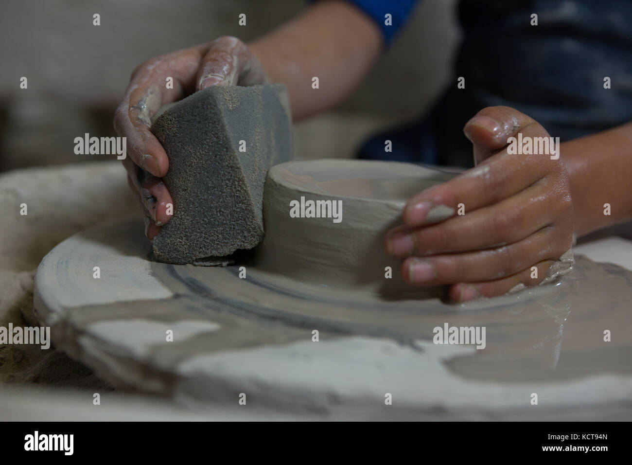 Mid section of girl using sponge while molding a clay Stock Photo - Alamy