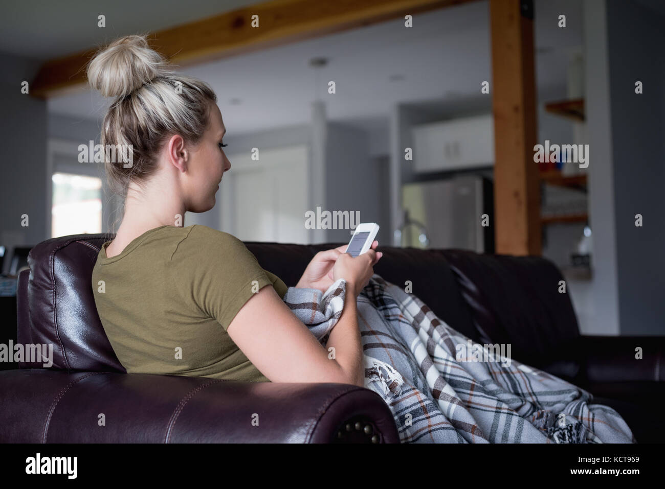 Woman using mobile phone while relaxing on sofa at home Stock Photo - Alamy