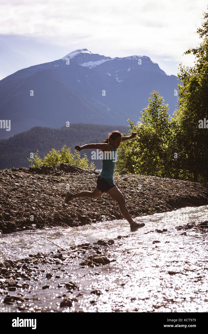 Jogger jumping through flowing water on sunny day Stock Photo - Alamy
