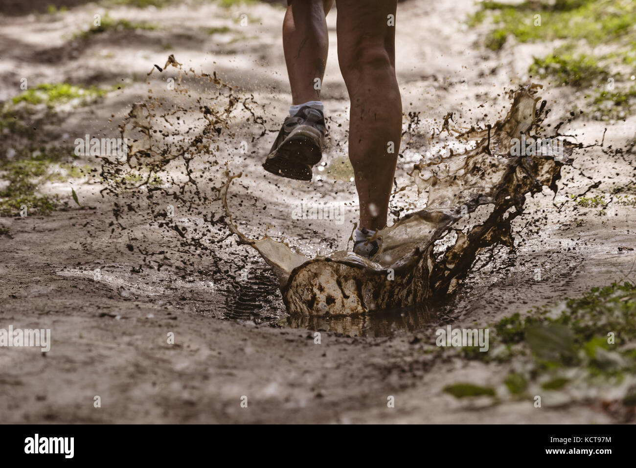Low section of jogger running through puddle Stock Photo - Alamy