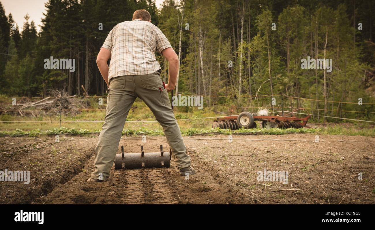 Farmer ploughing a field with agriculture equipment in farm Stock Photo ...
