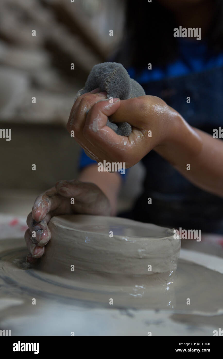 Mid section of girl using sponge while molding a clay Stock Photo - Alamy