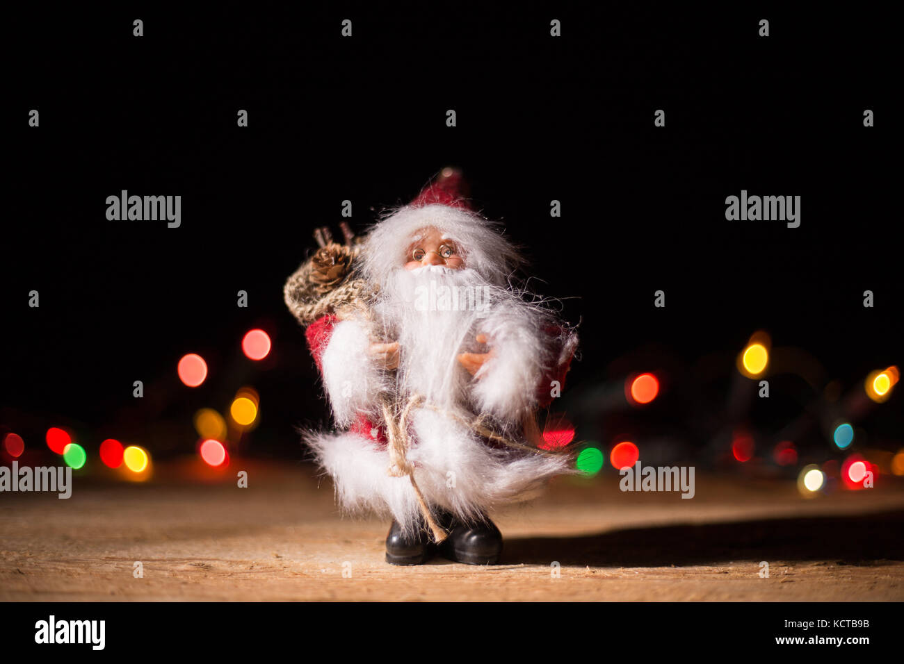 Santa Claus with presents standing on the wooden desk, blurred colorful ...