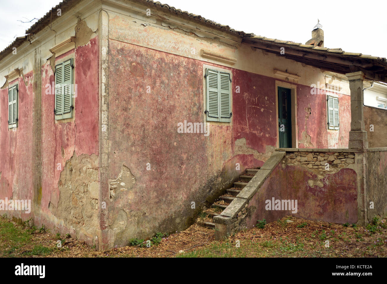 an old greek building in a poor state of repair with peeling green and ...