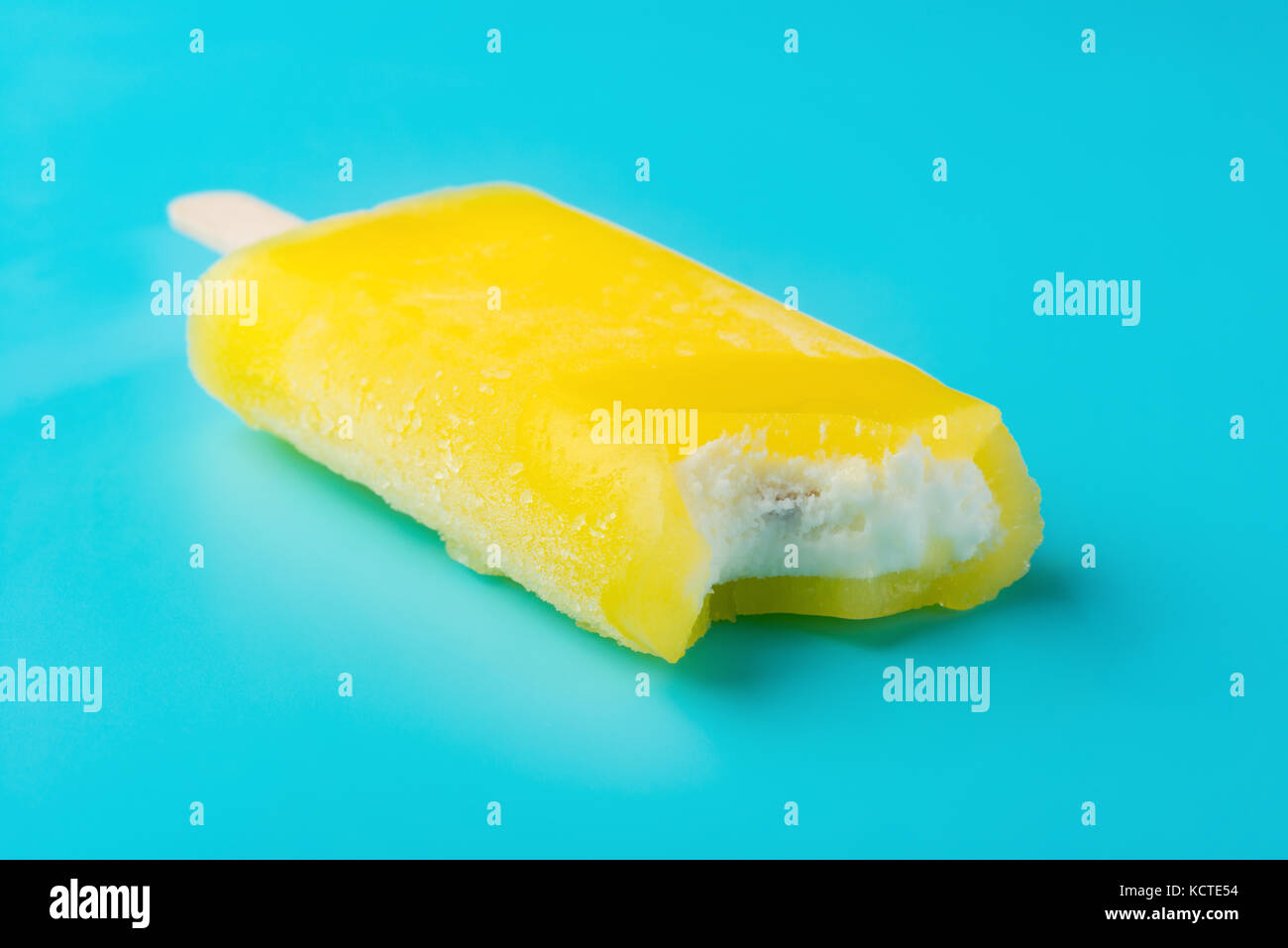 yellow popsicle with bites on a blue background Stock Photo - Alamy