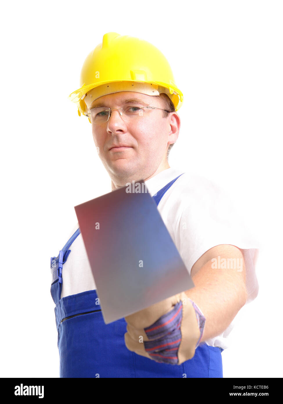 Construction worker wearing blue overall and yellow helmet holding ...