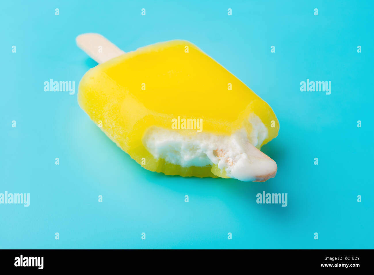 yellow popsicle with bites on a blue background Stock Photo - Alamy