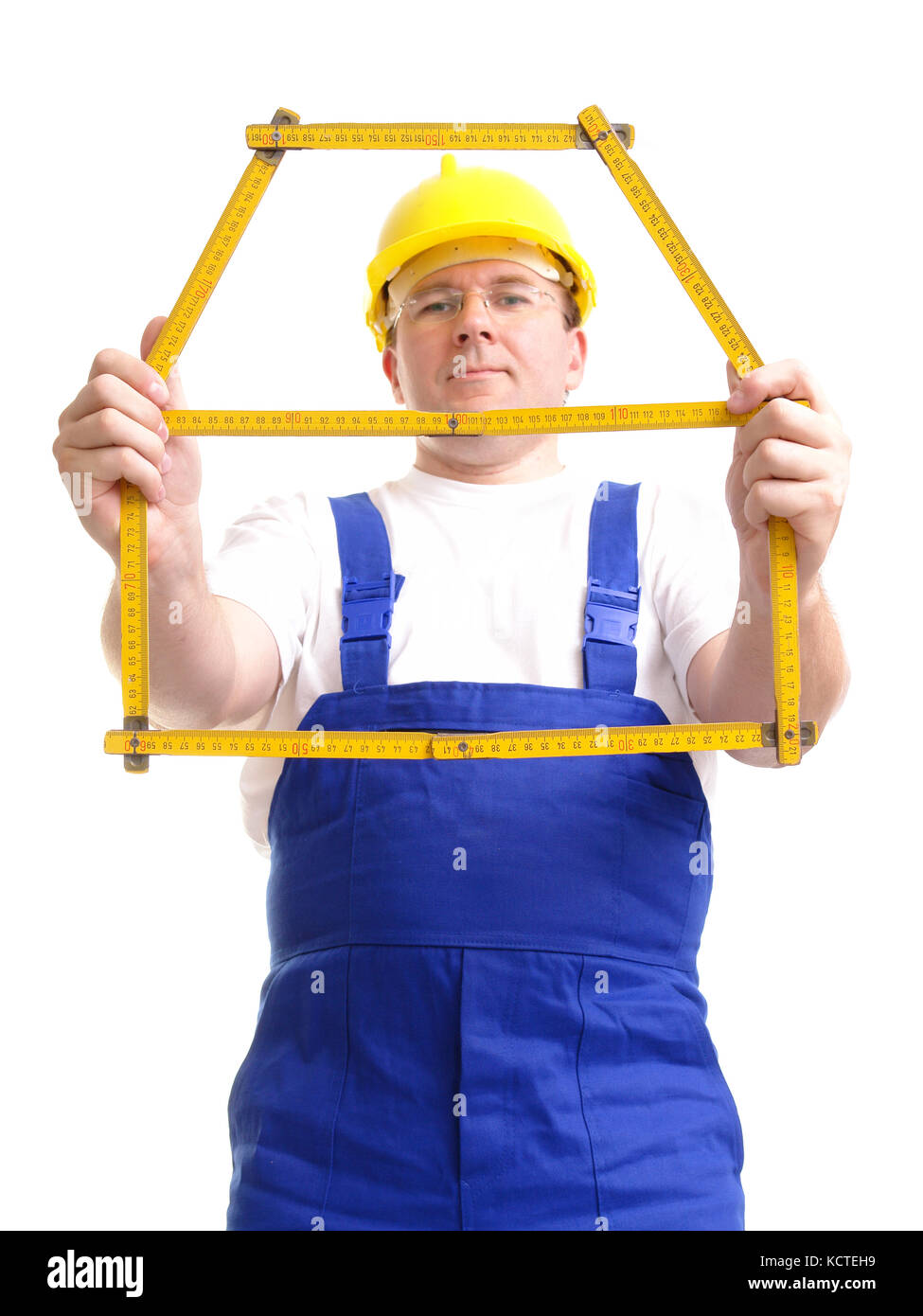 Builder wearing blue jumpsuit and yellow helmet holding unfolding ...
