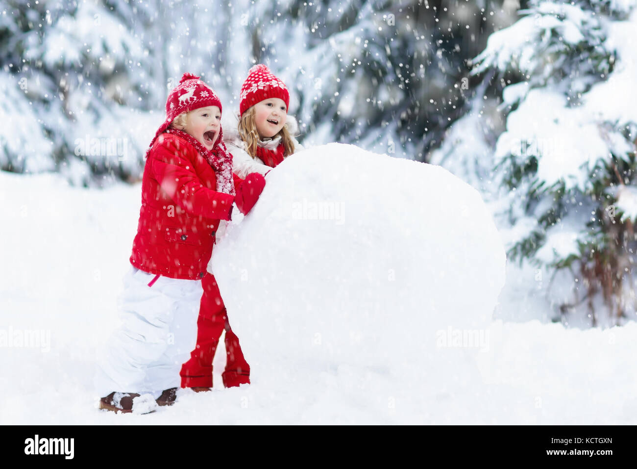 Children build snowman. Kids building snow man playing outdoors on ...