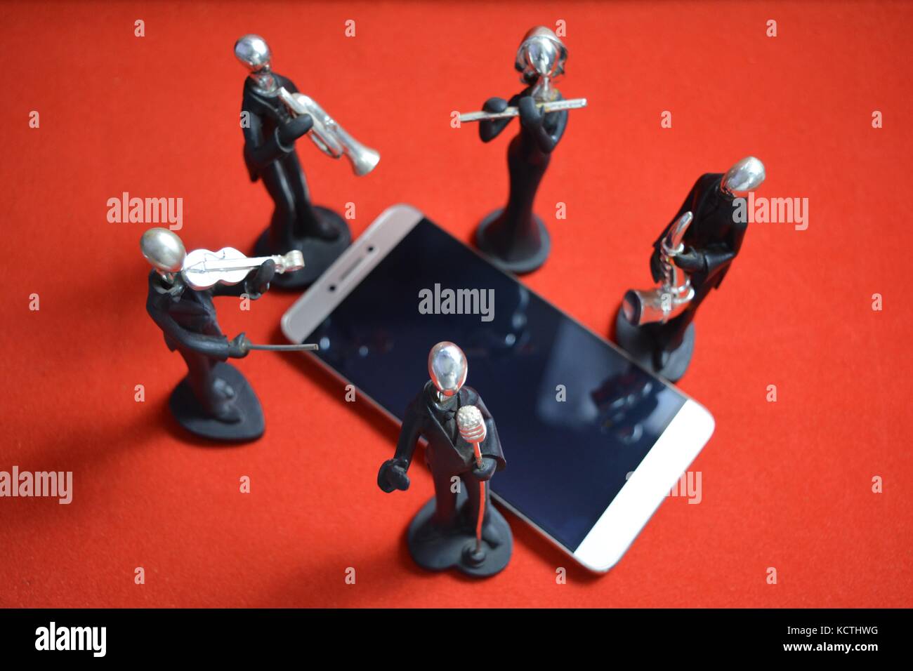 Toy man with microphone and musicians with mobile on the red background ...