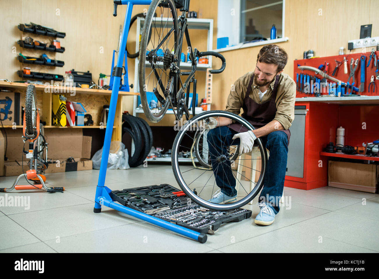 Repair specialist holding bicycle wheel over toolkit while checking it ...