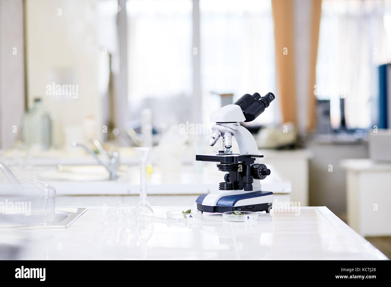 Modern binocular microscope and laboratory glassware prepared for ...