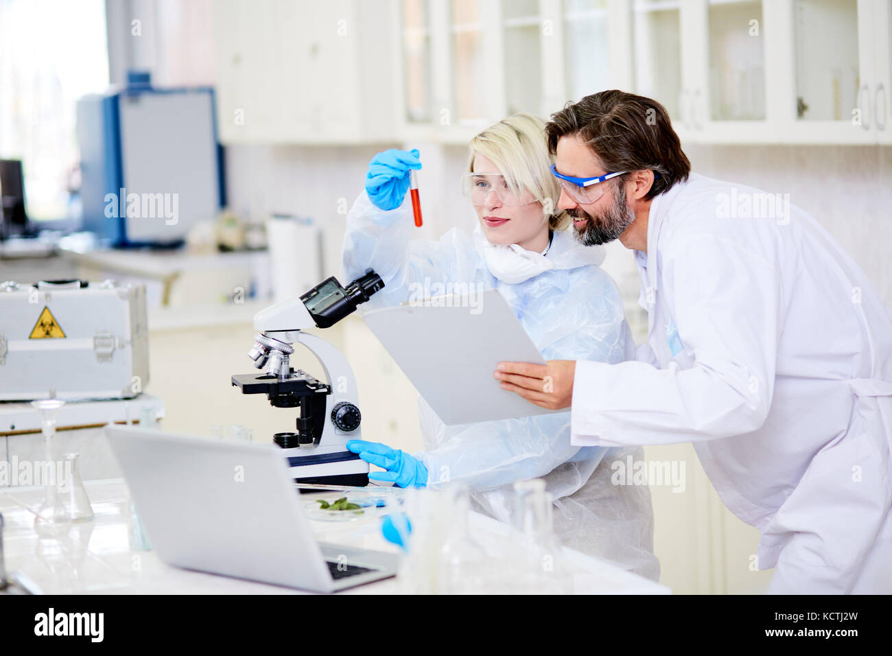 Cheerful group of microbiologists wearing safety goggles looking at ...