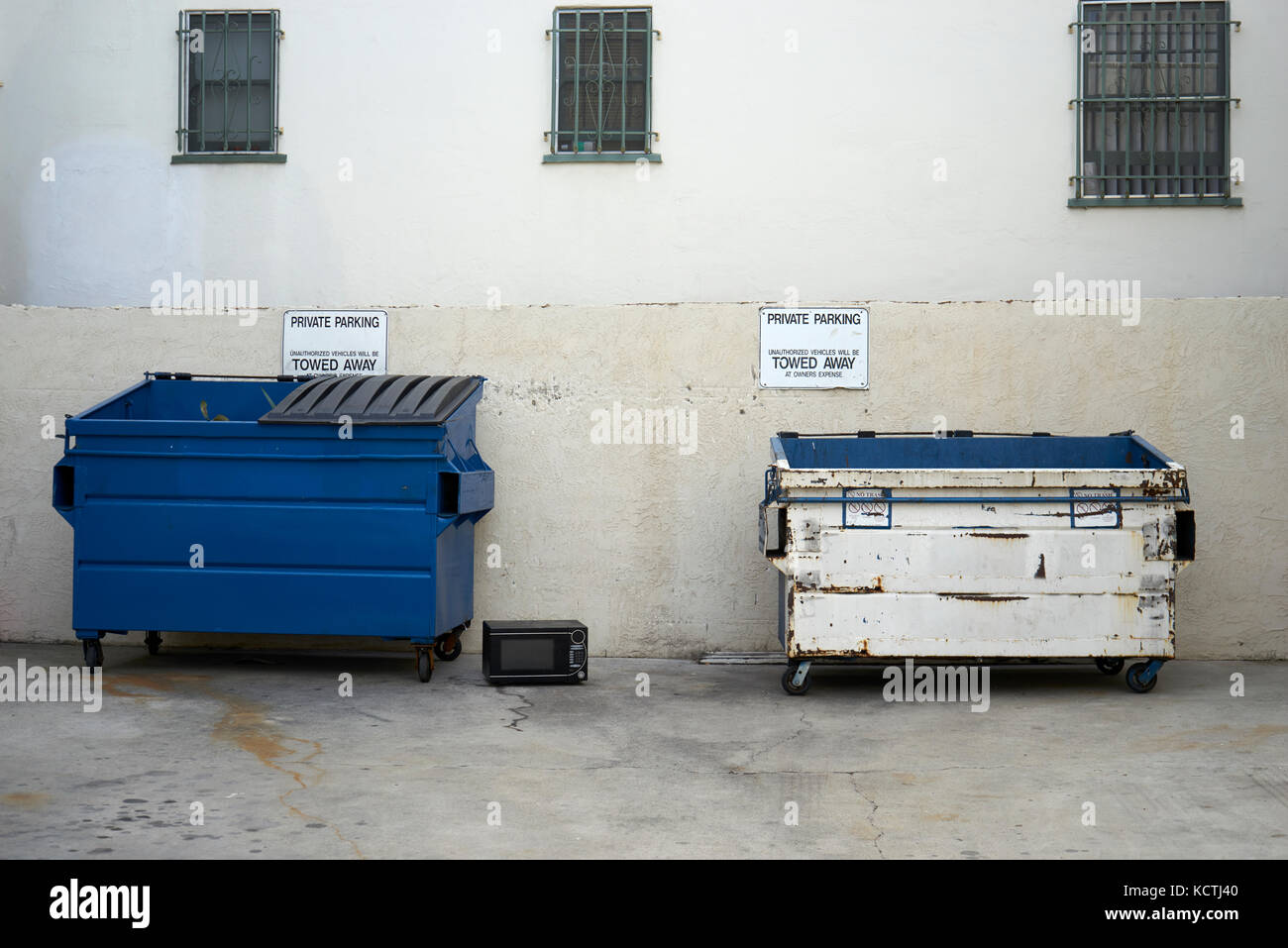 private parking signs above two commercial trash containers Stock Photo ...