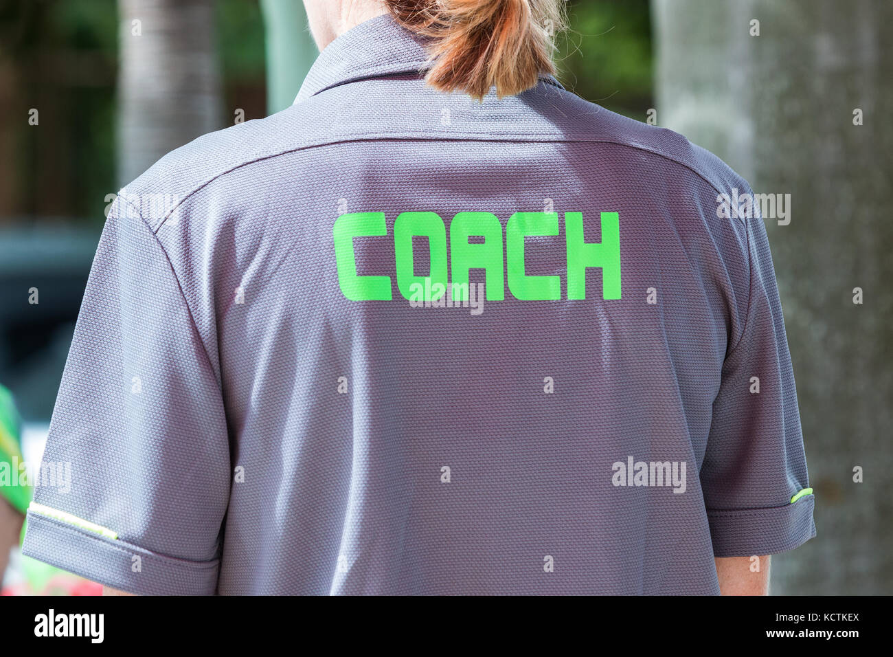 back of a coach's grey shirt with the green word Coach written on it ...