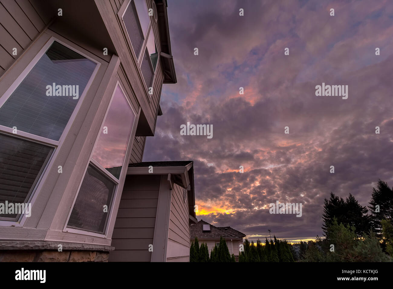 Reflection of sunset sky on windows of suburban neighborhood home in ...