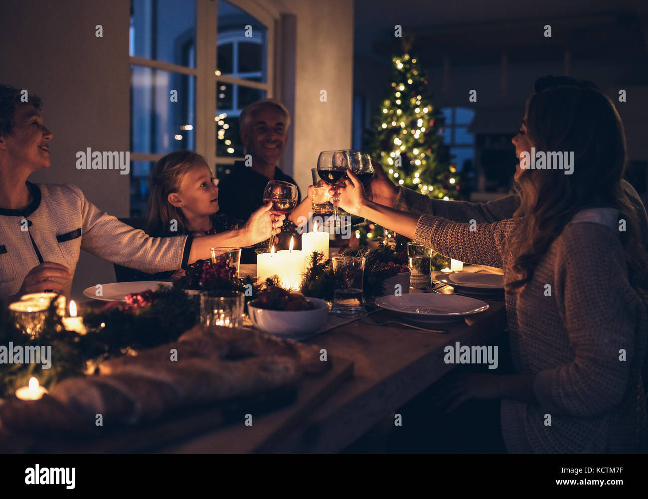 Family toasting with wine in a christmas dinner at home in the living ...