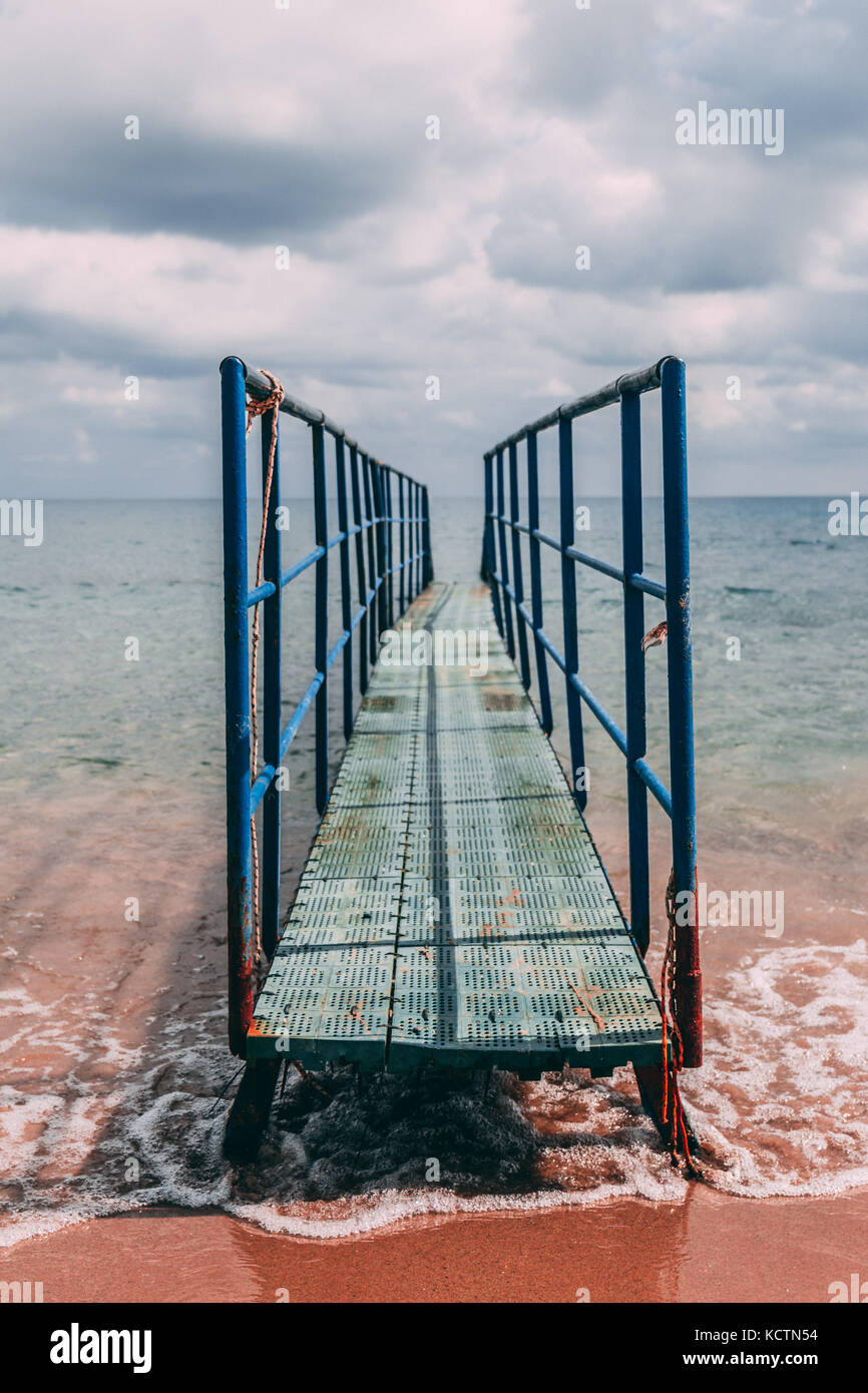 Old rusty bridge leading into the sea Stock Photo - Alamy