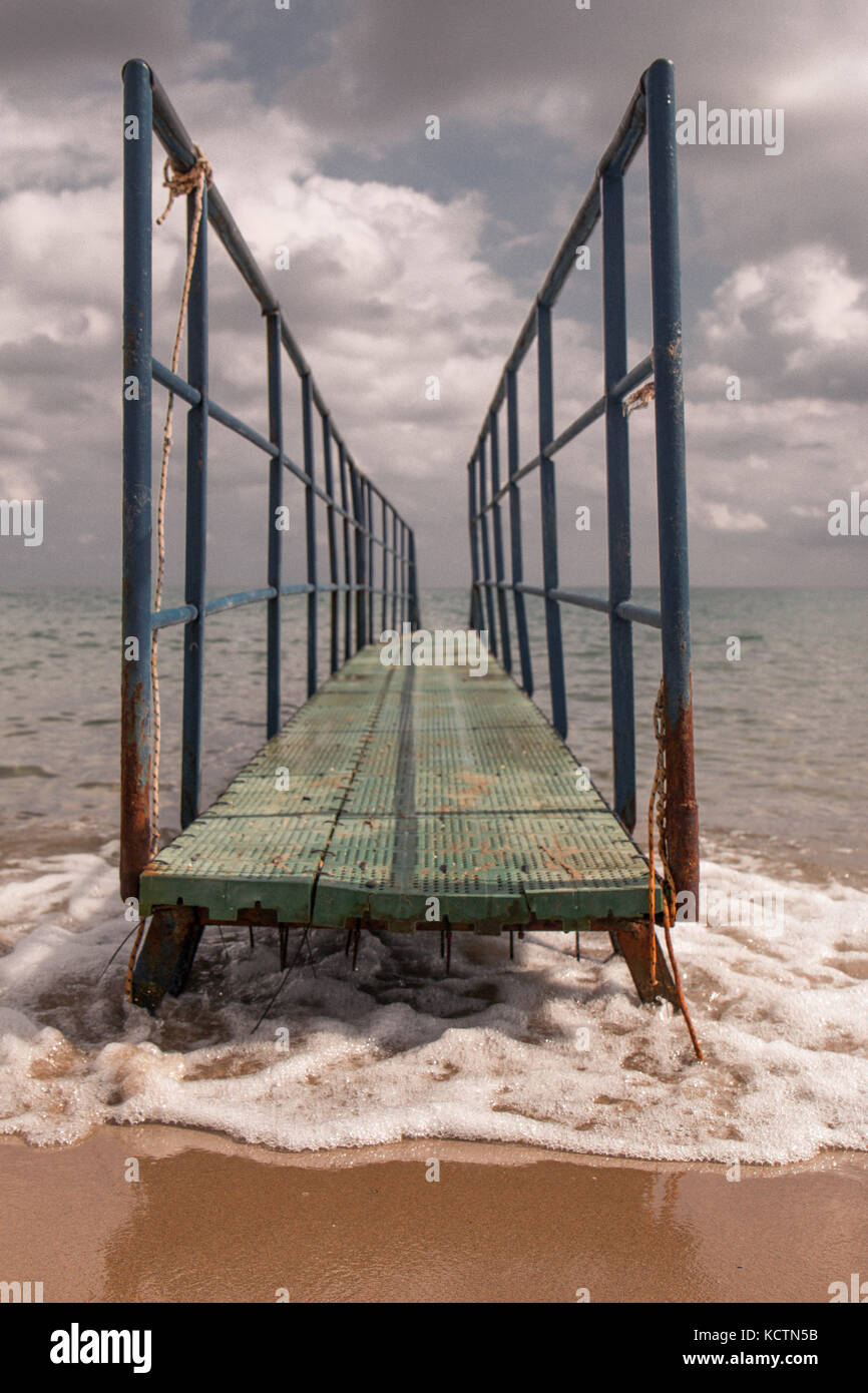 Old rusty bridge leading into the sea Stock Photo - Alamy