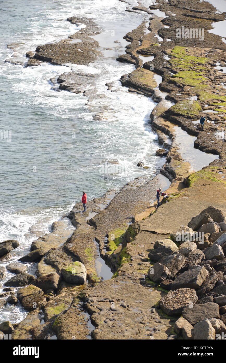 A lone figure on the rocks near the coastal path at Filey, North ...