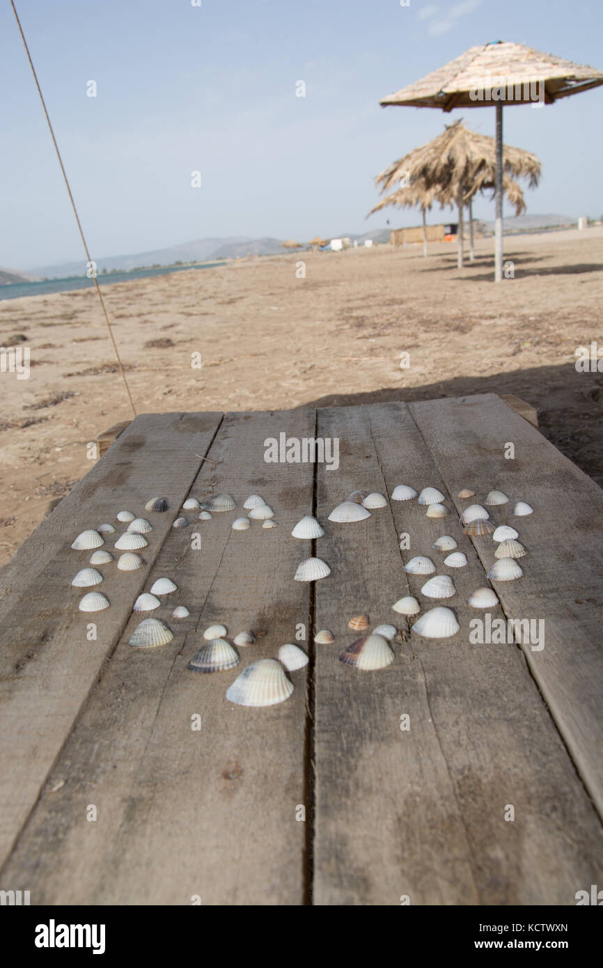 Seashells shaping a heart in a wooden table Stock Photo - Alamy