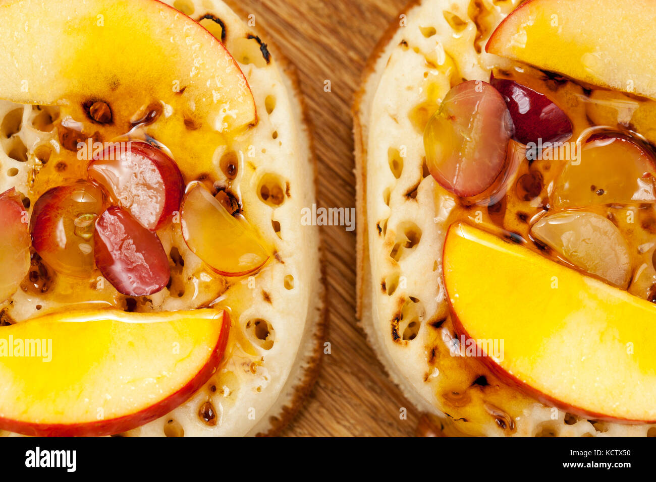 Close up shot of crumpets topped with apple segments, sliced grape and ...