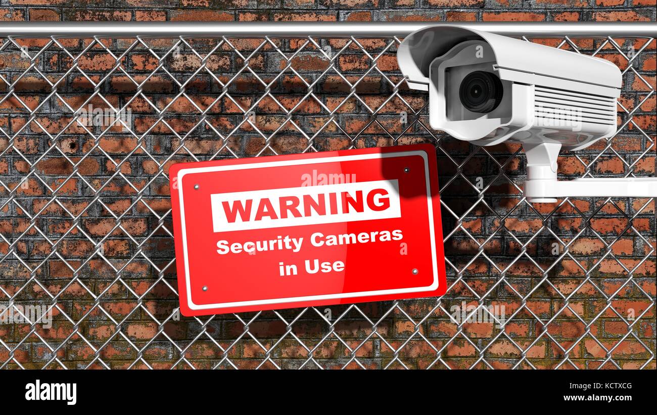 Security surveillance camera on chain-link fence with warning sign ...