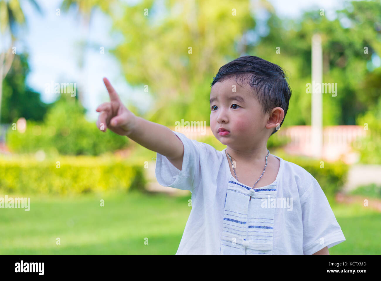 Asian little Kid pointing up by fingers to something or empty copy ...