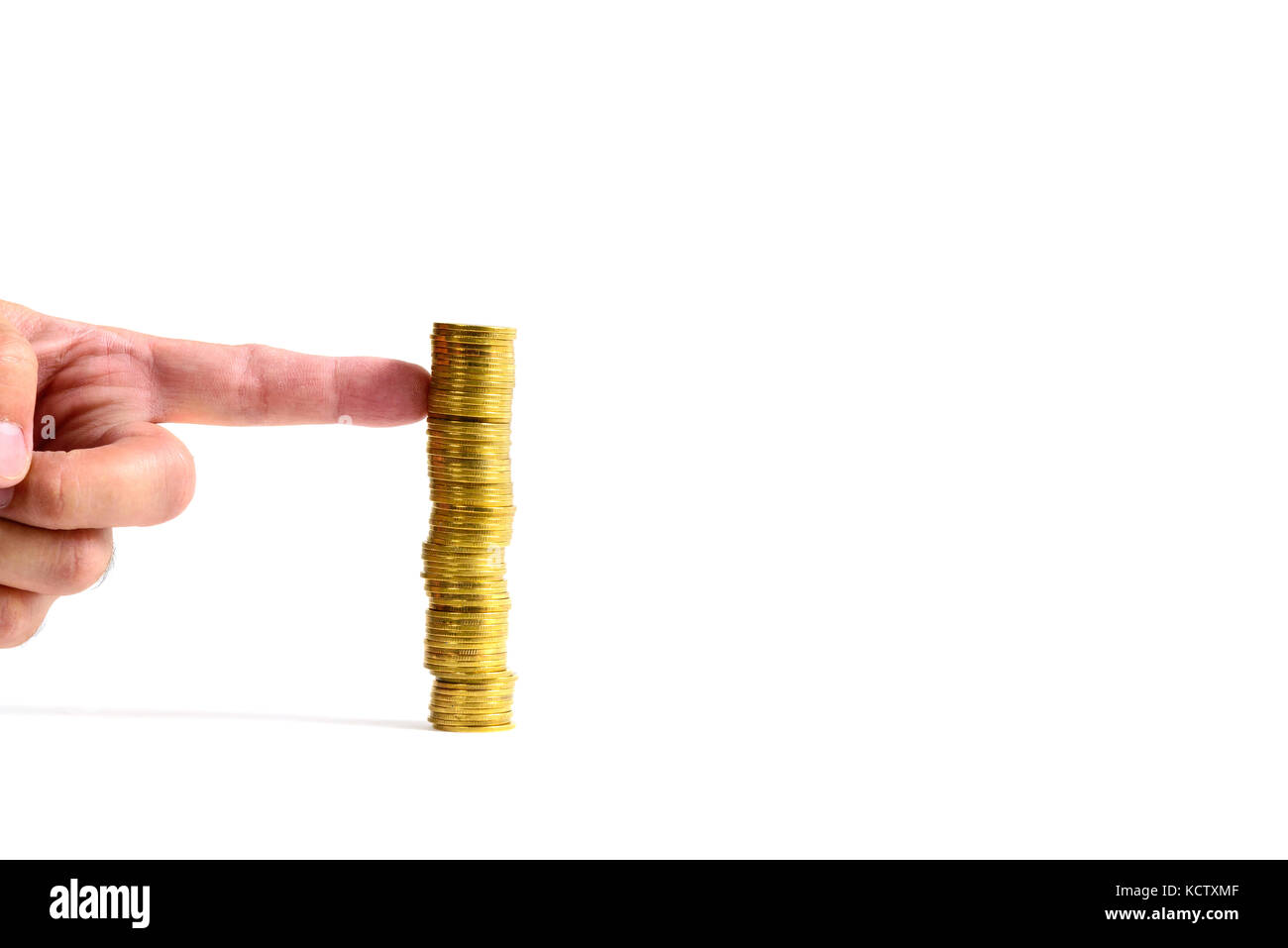 Finger pushing a pile of gold coins, column of golden coins falls ...