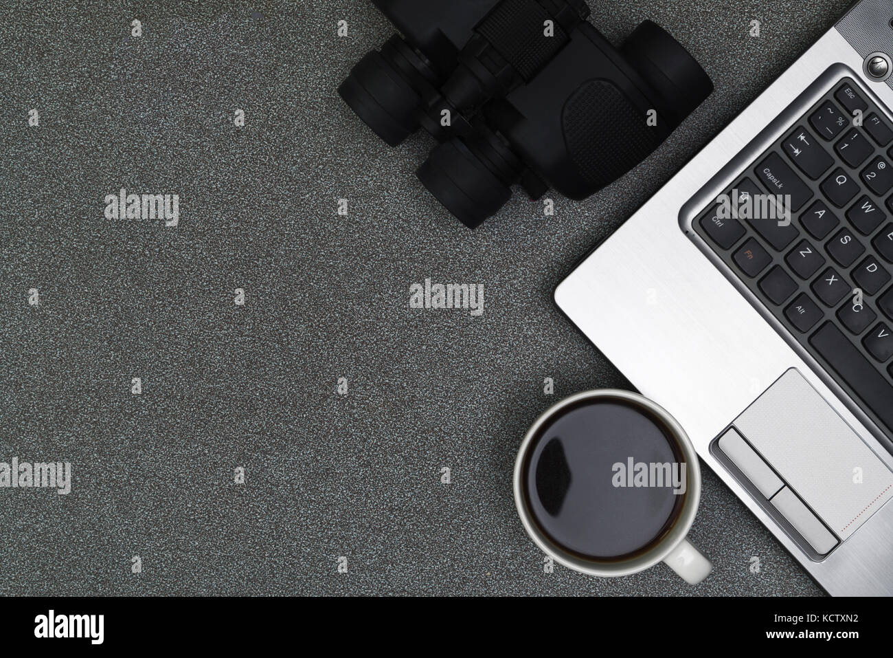 Laptop computer or notebook, binocular and cup of coffee on gray color ...