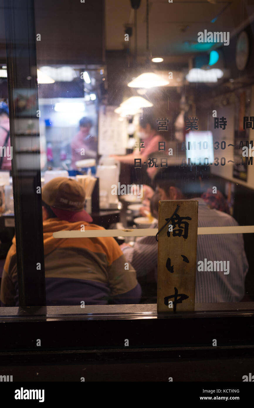 Night shot through restaurant window of two customers, staff light by ...
