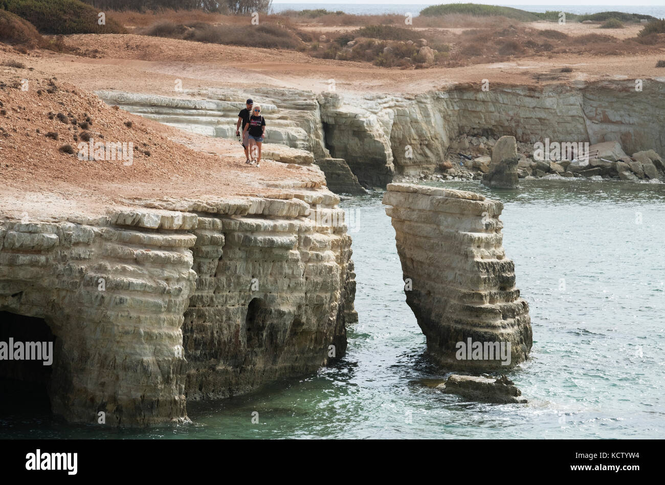 Two people walking along the cliffs at Sea caves near Peyia Paphos ...
