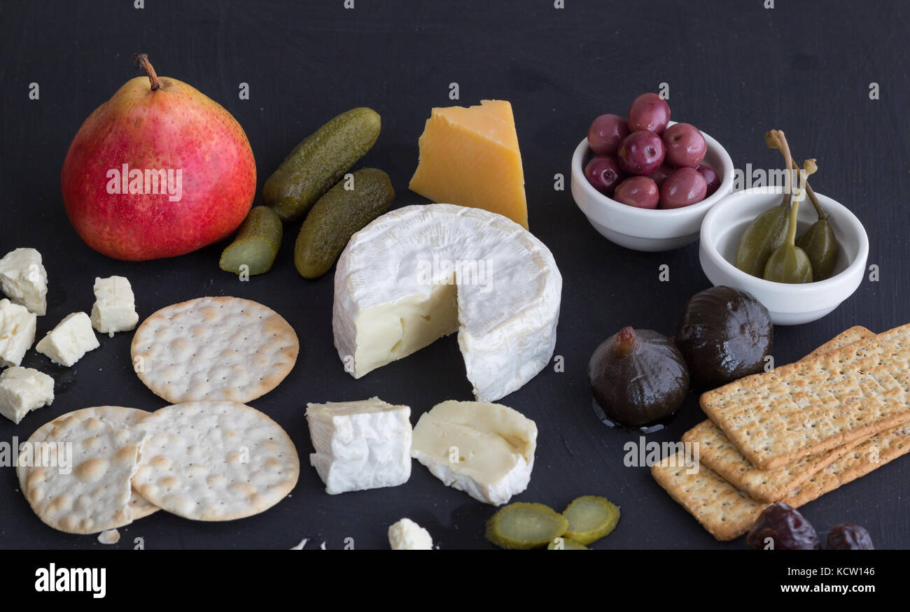 Cheese,crackers, pickles and fruit on black background close up Stock ...