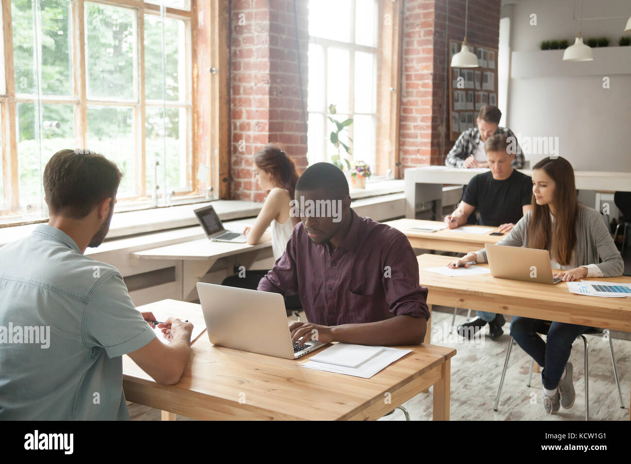 Multiethnic group of casual coworkers at work in shared loft office ...