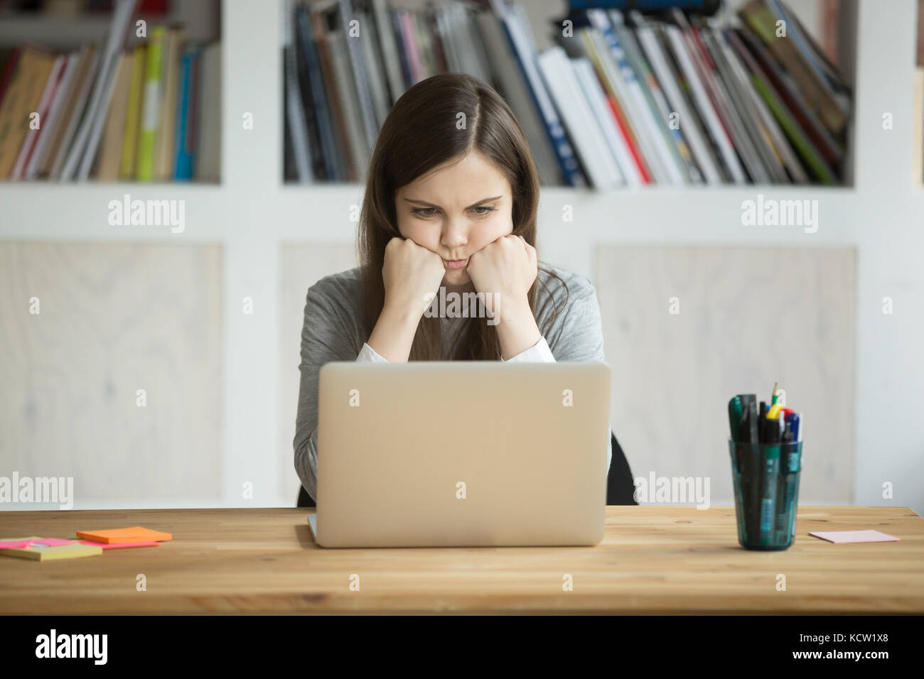 Grumpy not amused office worker looking at laptop screen in office ...
