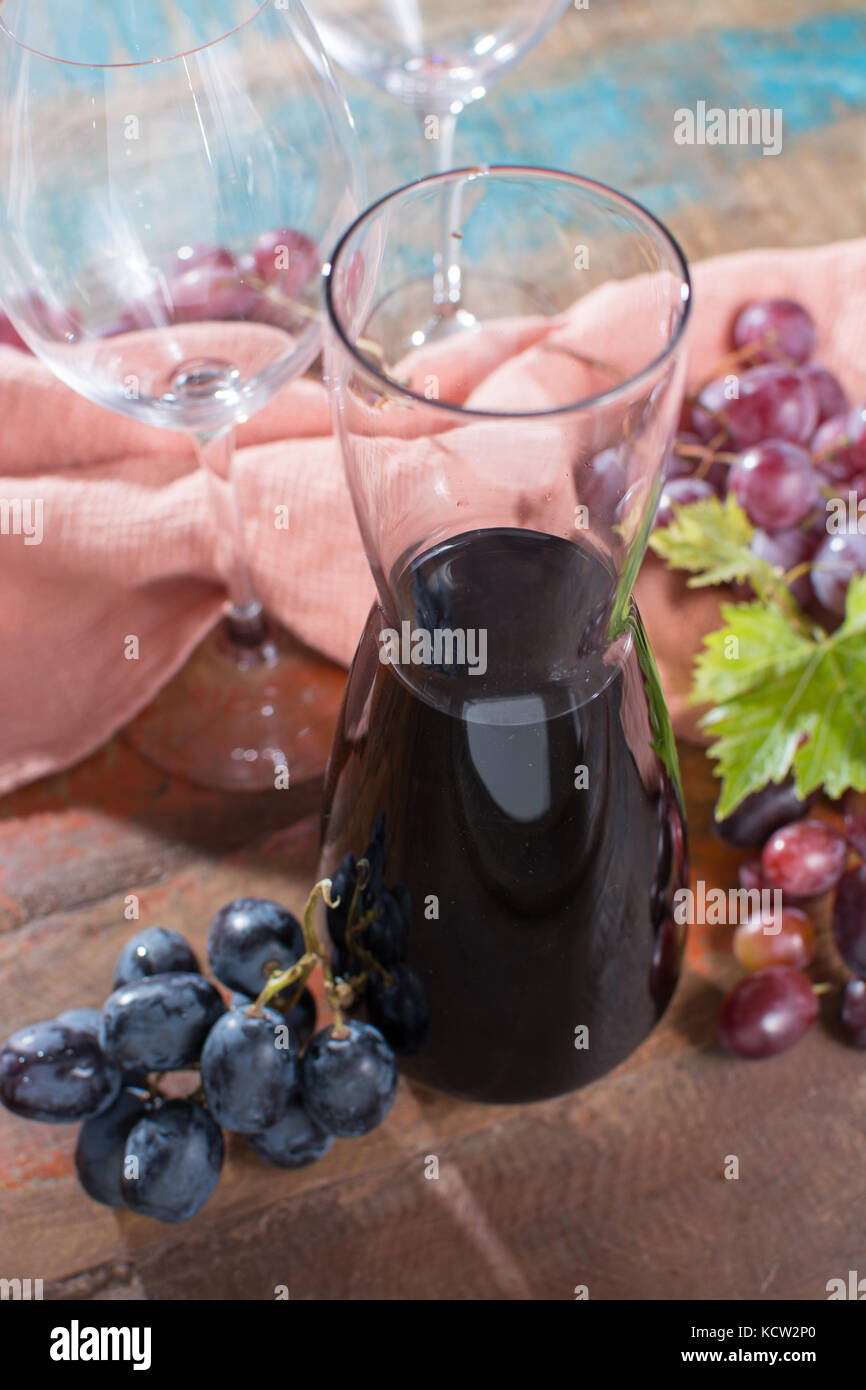 Small carafe with dry red wine, two wine glasses and grapes on the ...