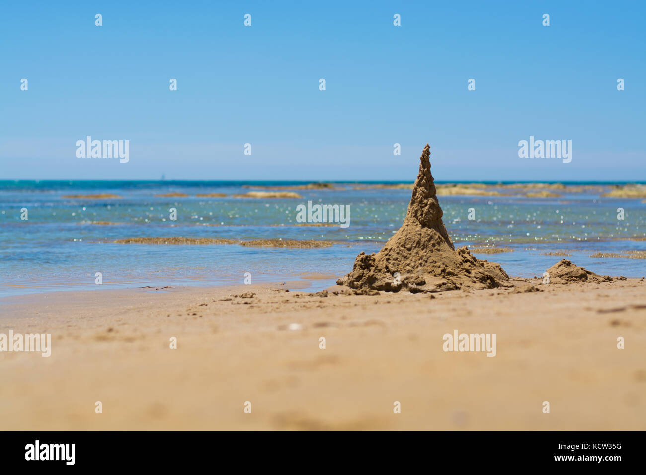 Sand castle on the beach with crystal blue sea water Stock Photo - Alamy