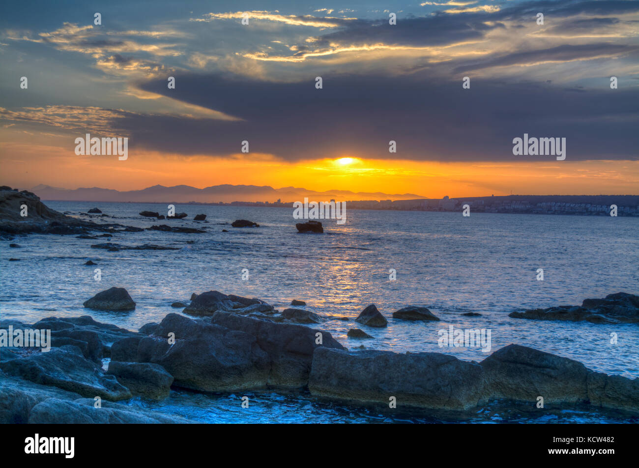 HDR image of a sunset over rocks in the sea on the Spanish island of ...