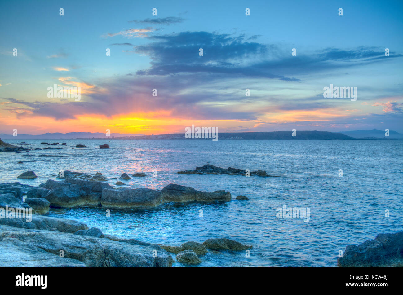 HDR image of a sunset over rocks in the sea on the Spanish island of ...