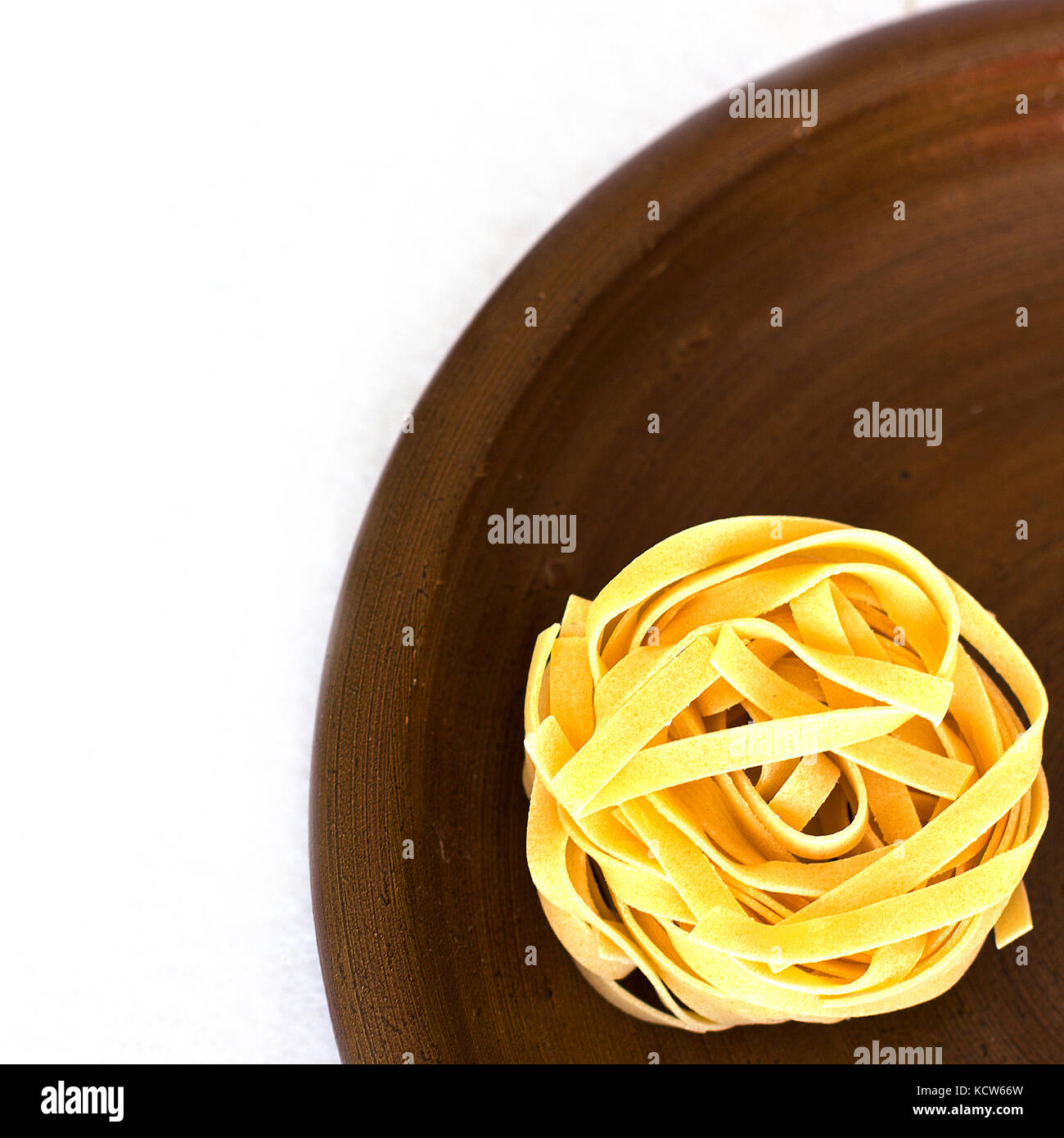 Uncooked tagliatelle on ceramic plate. Isolated Stock Photo - Alamy