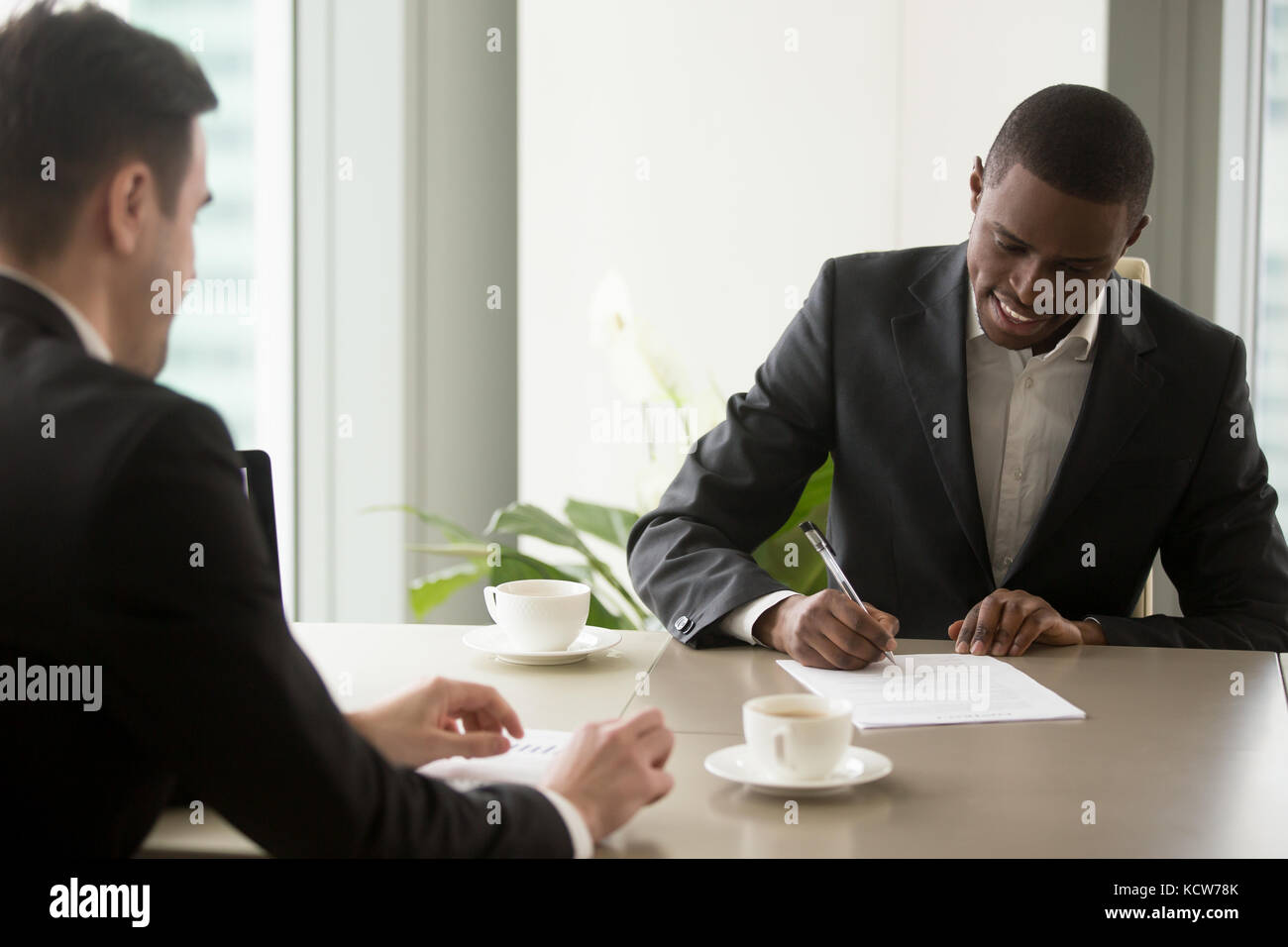 Happy african american businessman putting signature on paper document ...
