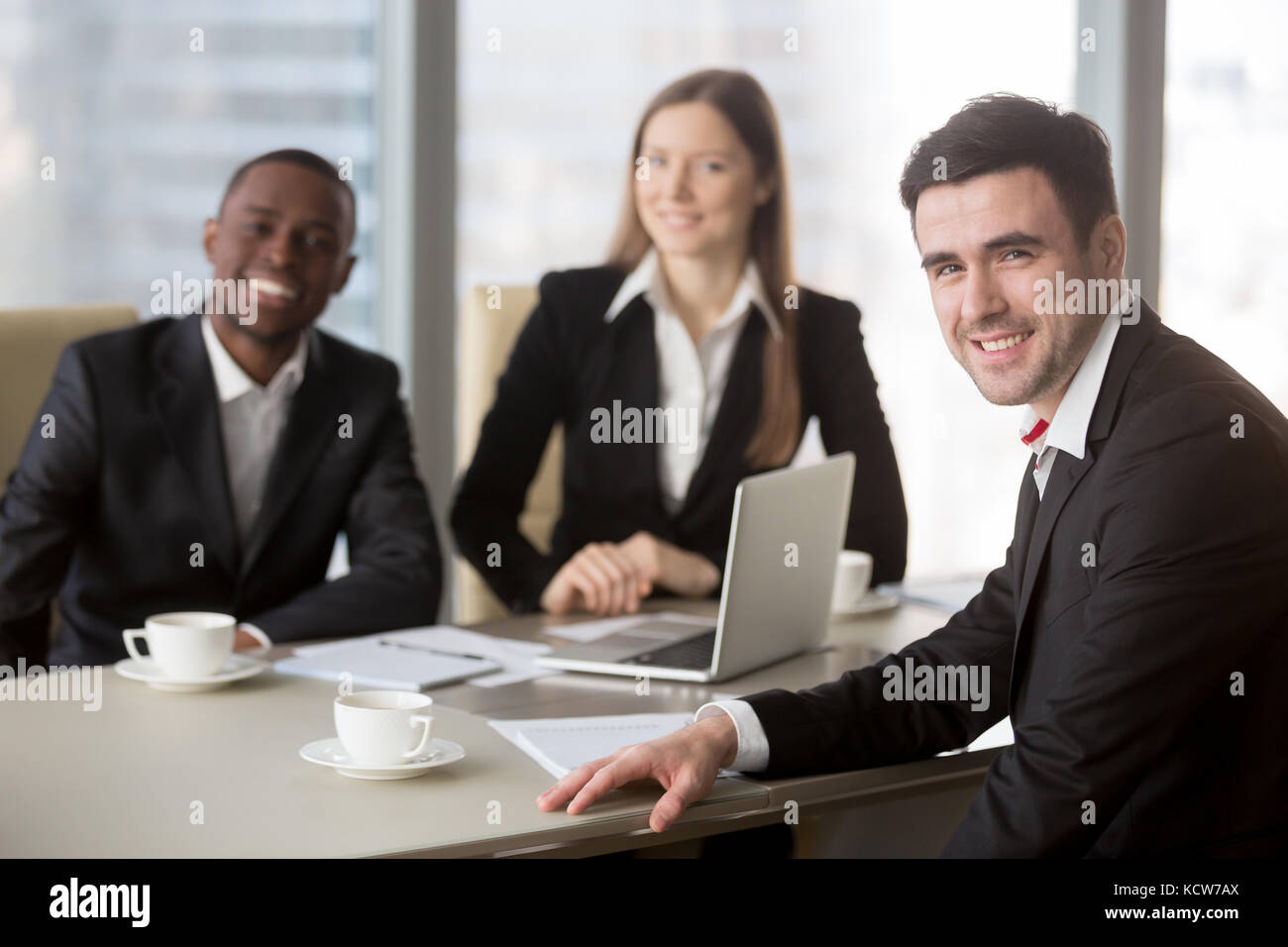 Portrait of friendly caucasian businessman sitting at negotiation table ...